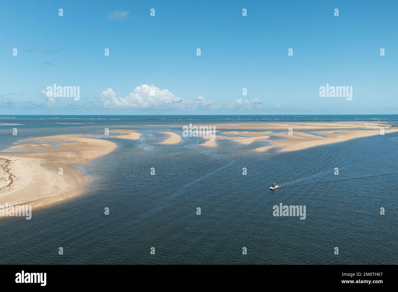 Small boat sailing in place where the river meets the sea - drone view ...