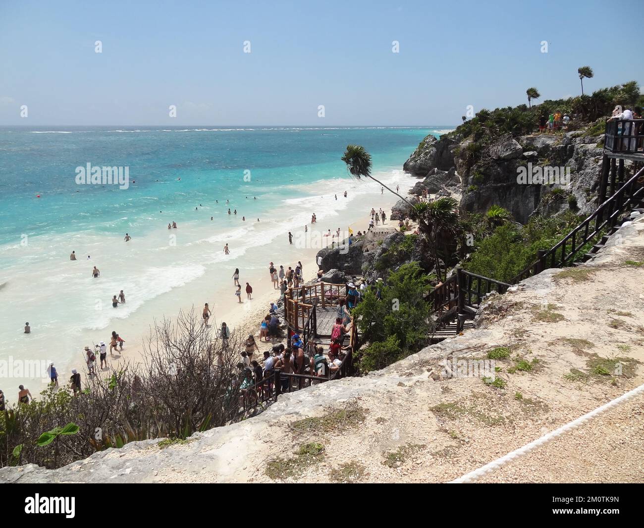 The Tulum Mayan Ruins on the seashore with people swimming in the water ...