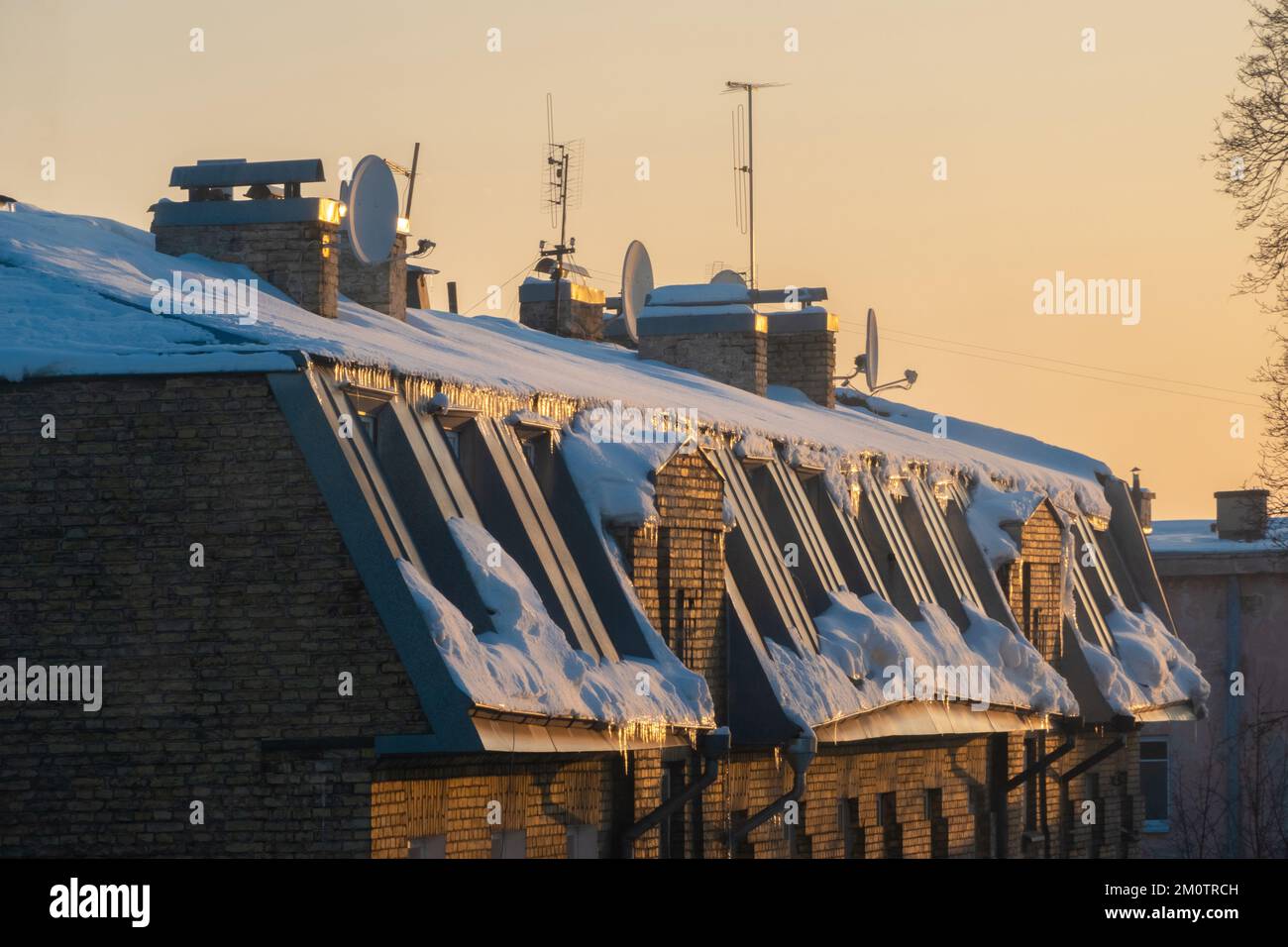 TV and cable antennas on the roof top of an apartment house covered in ...