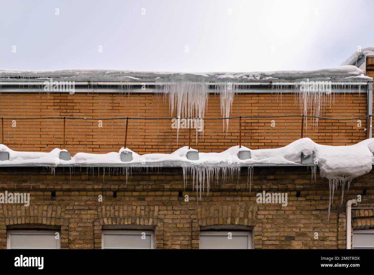 Sharp icicles hanging on the edge of the roof. Melting snow forms ...