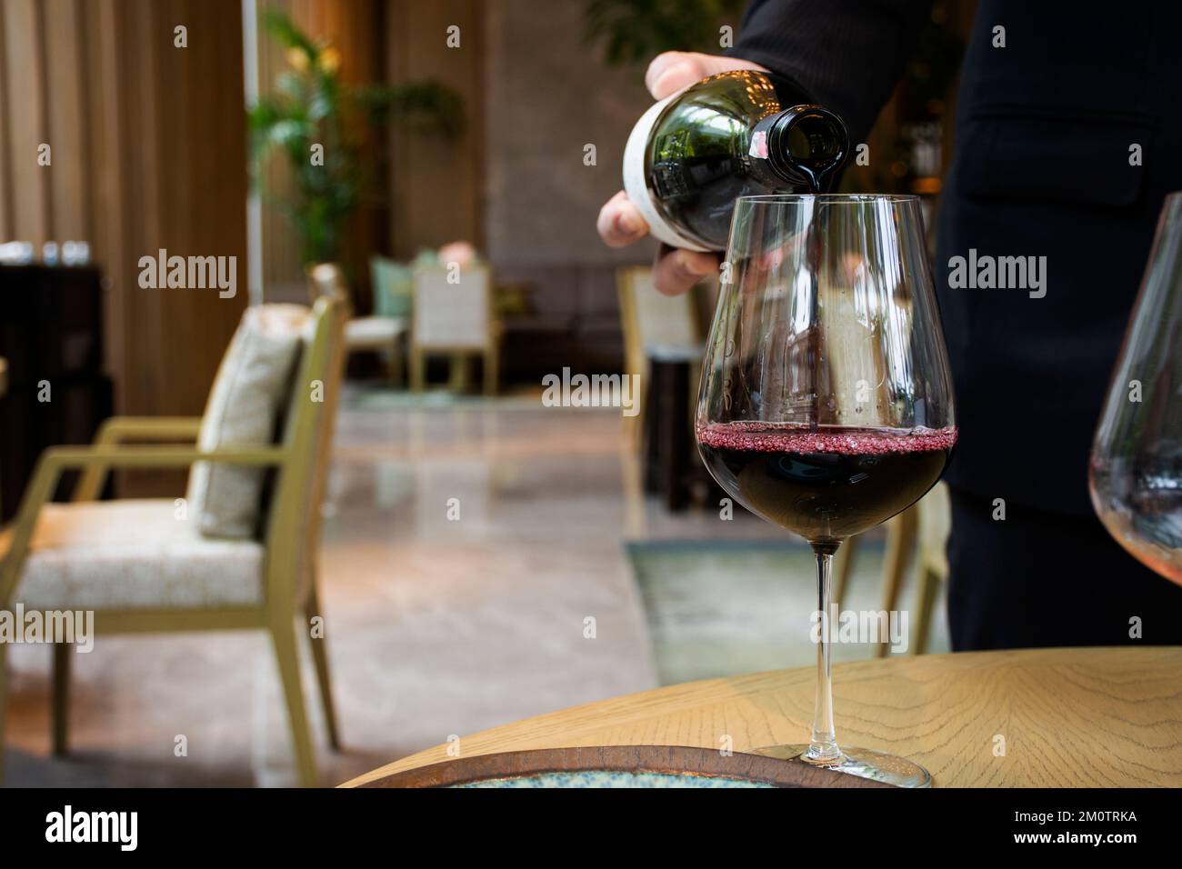 Thai restaurant manager and waiter pouring wine into glass for served ...