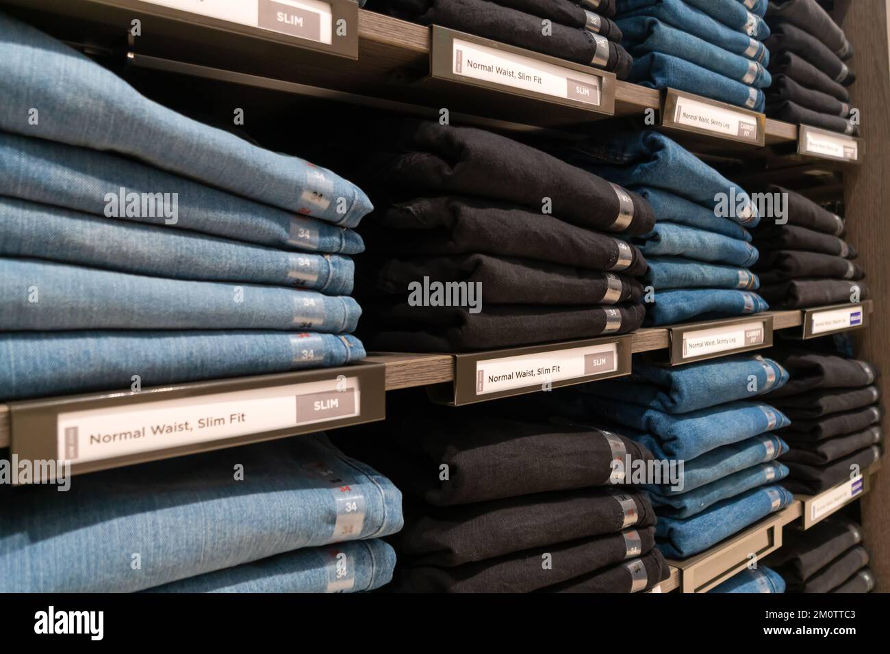 Close-up of a lot of jeans on the shelves in the store. Stack of jeans ...