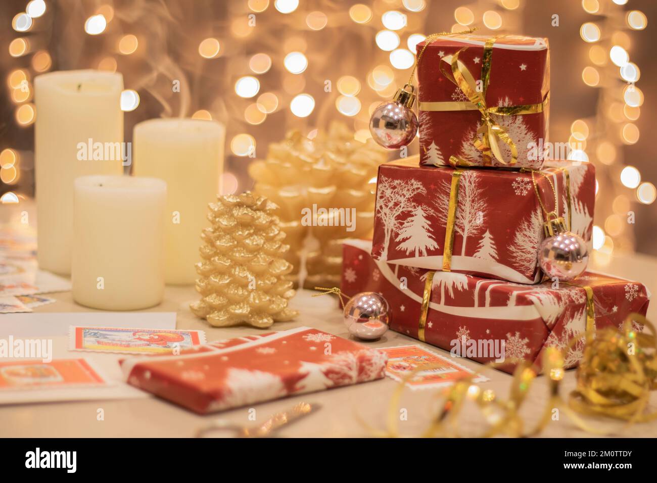 photo of lit candles and wrapped gifts in red paper with blurred lights ...