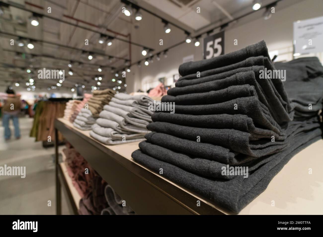 Soft cotton sweatpants of different colors are stacked on a shelf in a ...