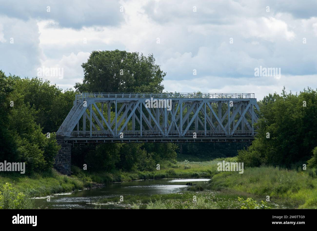 View of the steel railway bridge over a small river Stock Photo - Alamy