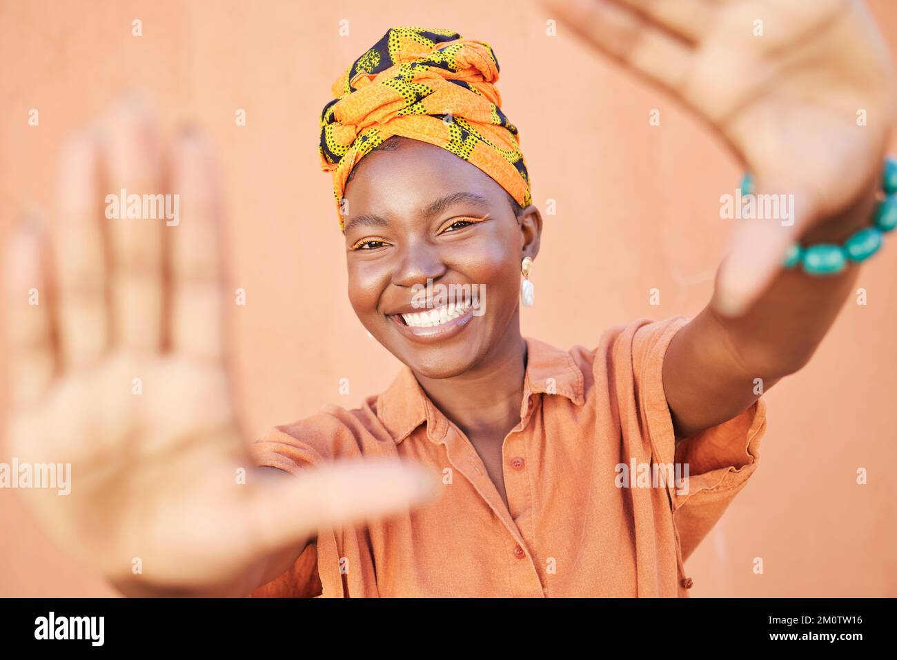 Fashion black woman, face or framing hands on orange wall background in city for profile picture ...