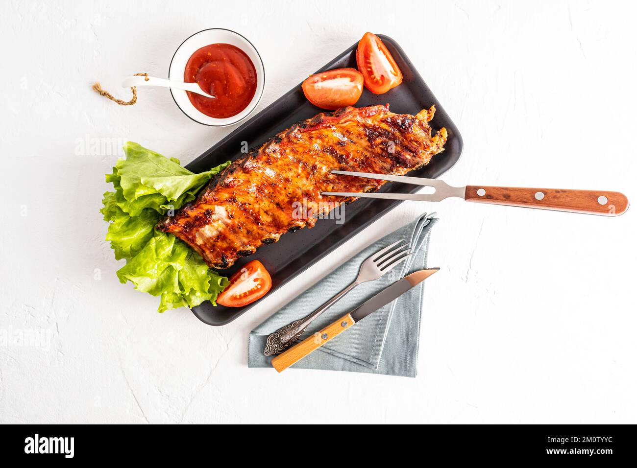 grilled pork ribs on a ceramic rectangular plate with fresh tomato ...