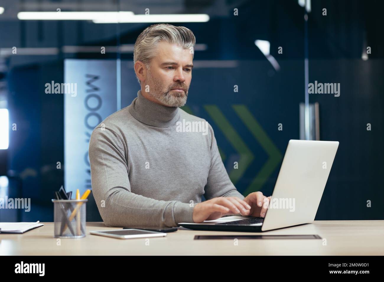 Serious and pensive mature investor working inside modern office ...