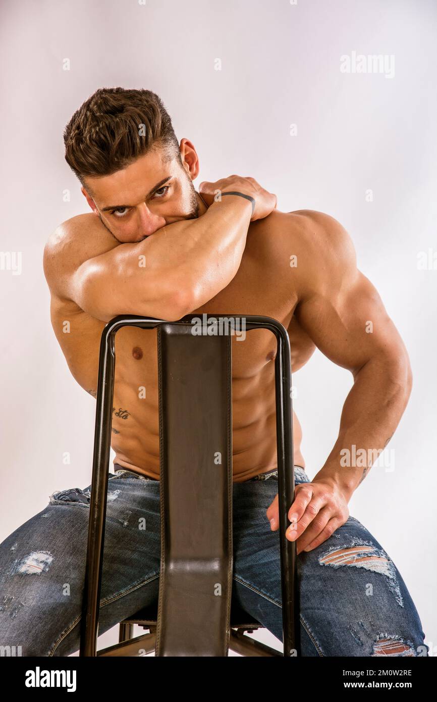 Muscular bodybuilder sitting on chair, looking at camera Stock Photo ...