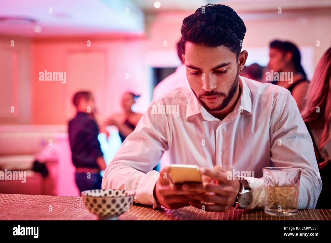 Phone, party and waiting with a man in a nightclub, checking his text ...