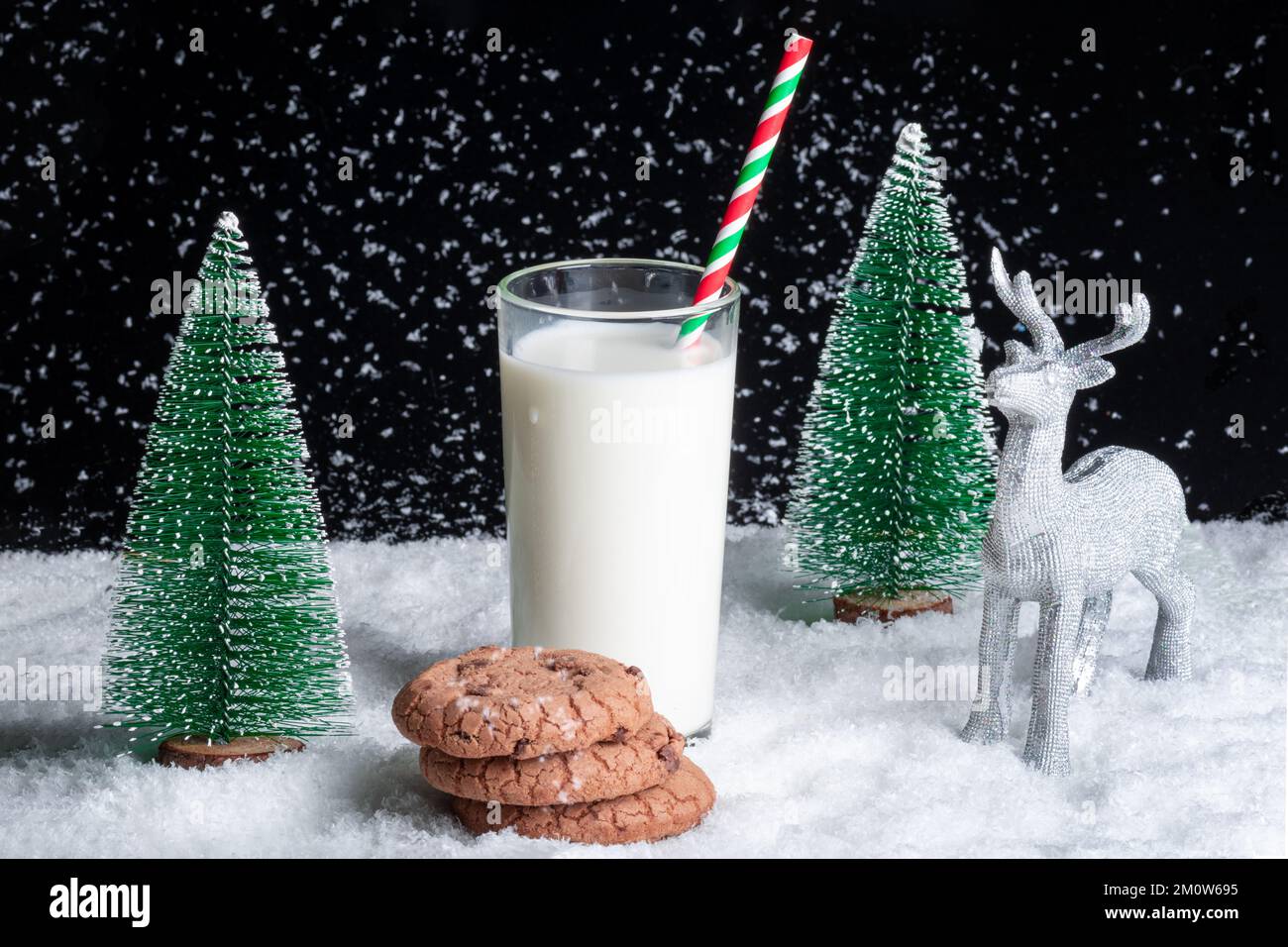 A gift for Santa. A glass of milk with a straw and cookies with ...