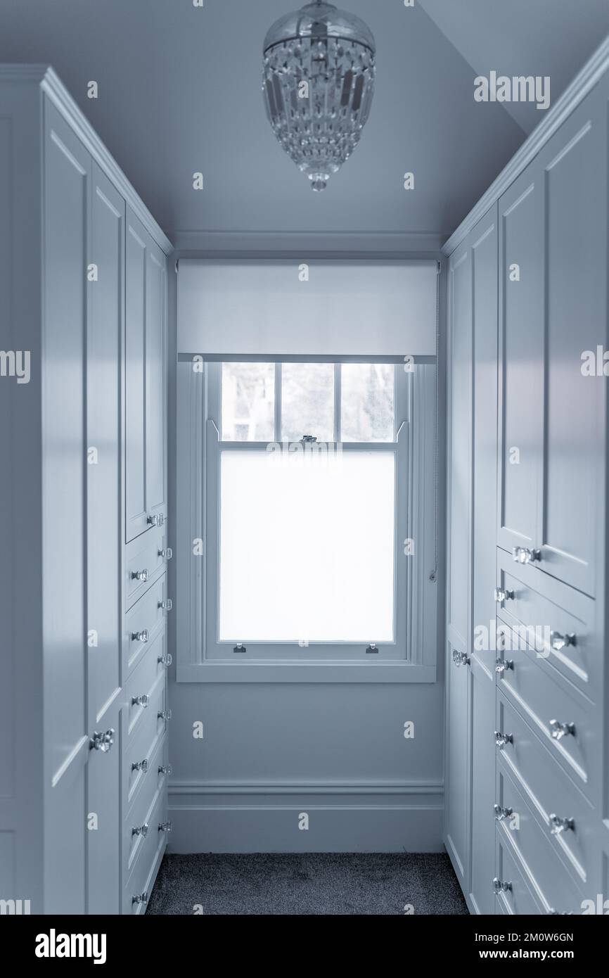 The vertical view of a window in a dressing room with drawers and ...