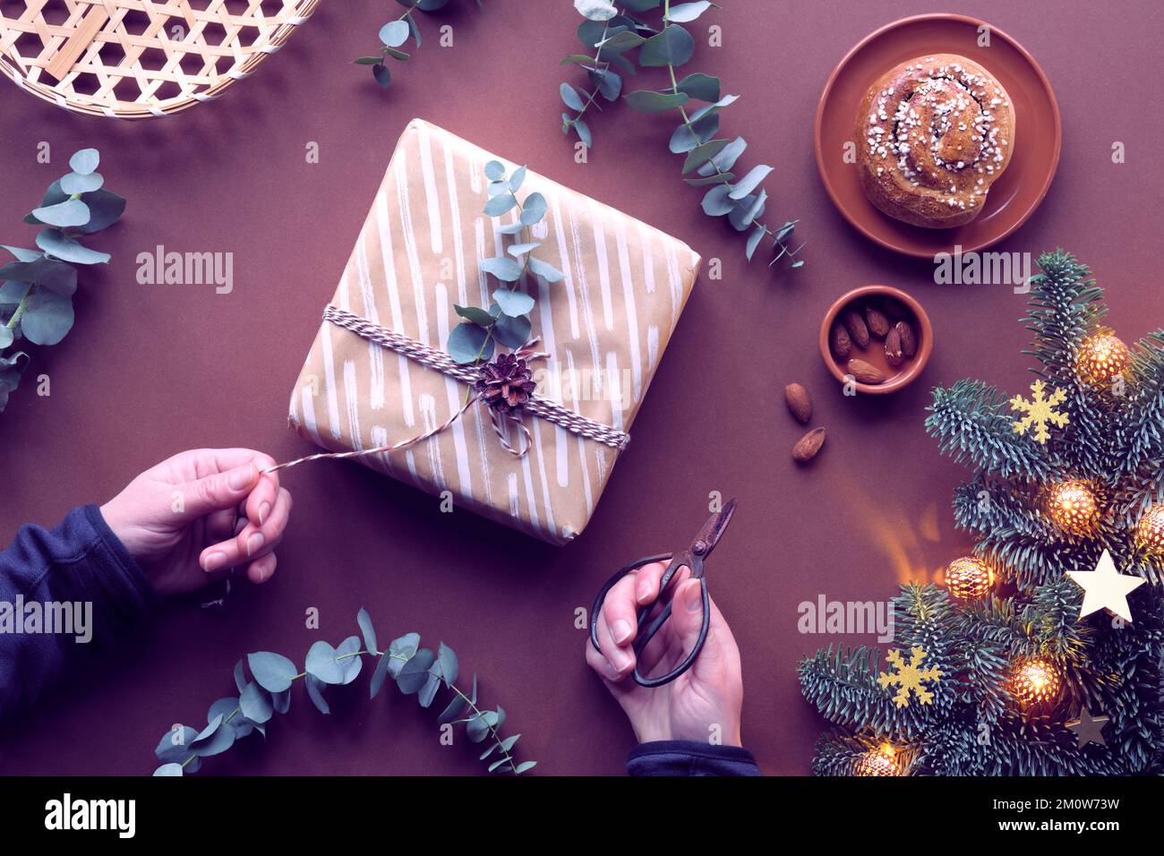 Chestnut brown Christmas background. Hands wrapping Xmas gift box. Flat ...