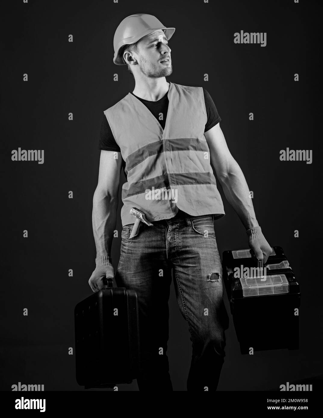 Man in helmet, hard hat holds toolbox and suitcase with tools, blue ...