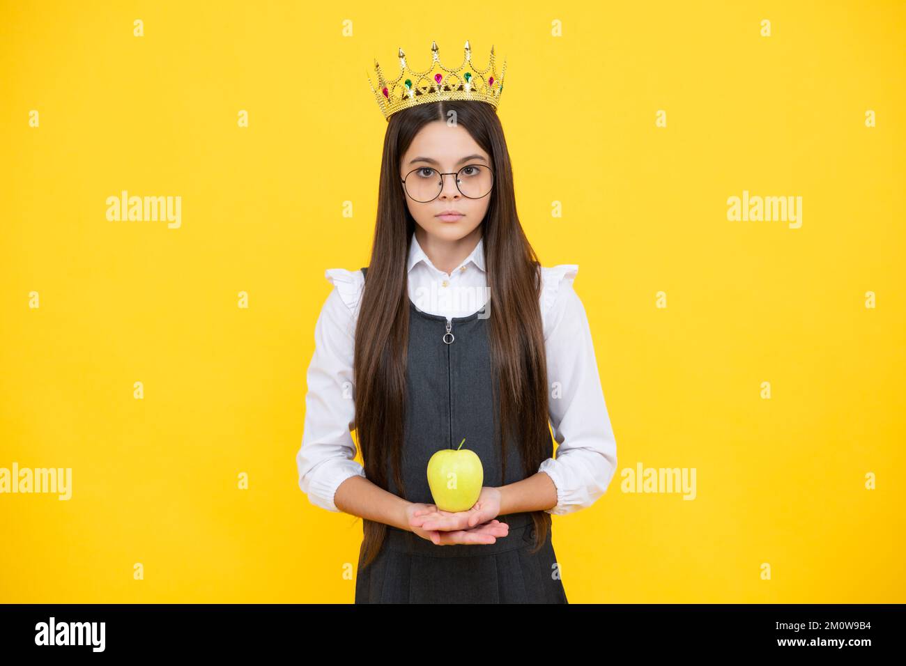 Teen child in queen crown hold apple isolated on yellow background ...