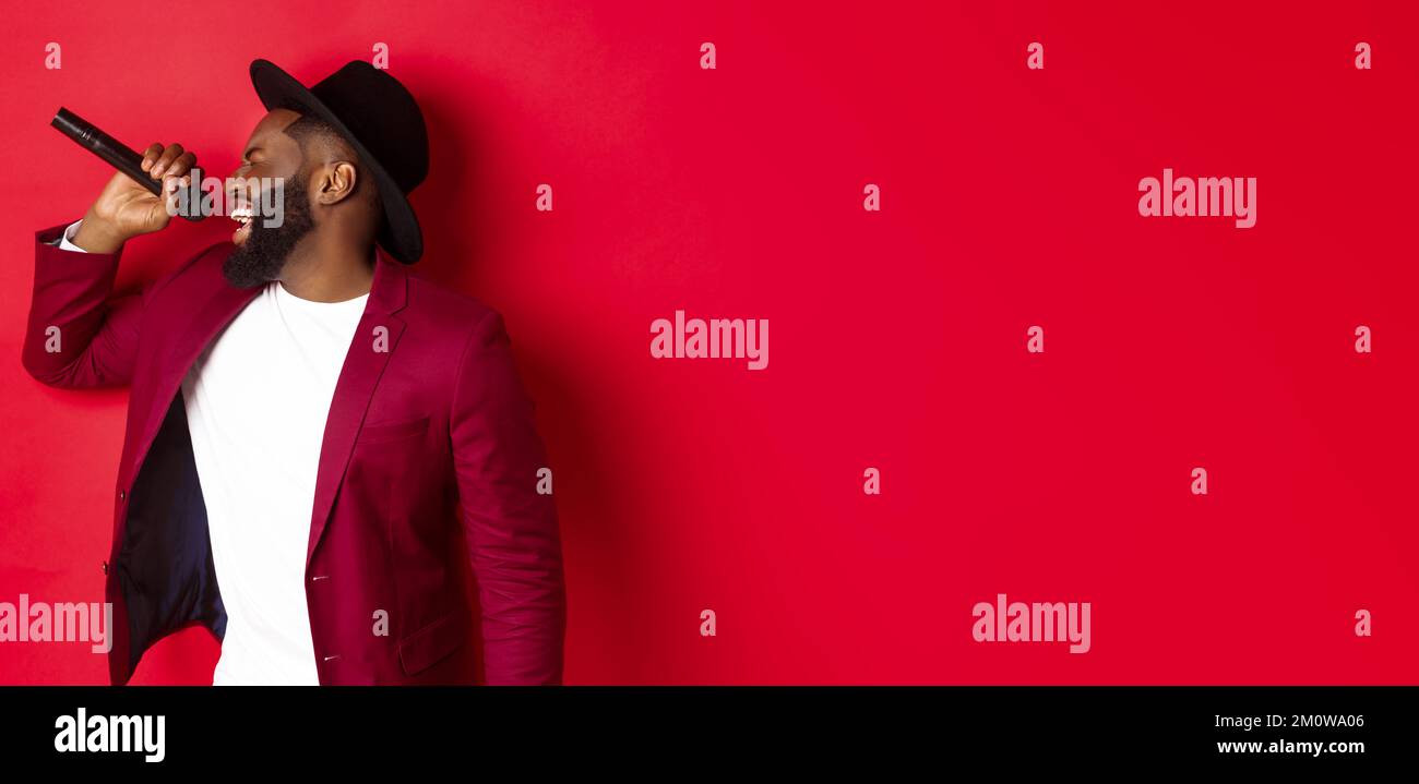 Passionate black male singer performing against red background, singing ...