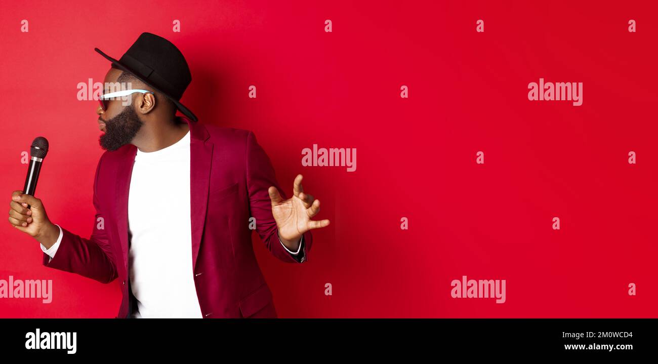 Passionate black male singer performing against red background, singing ...