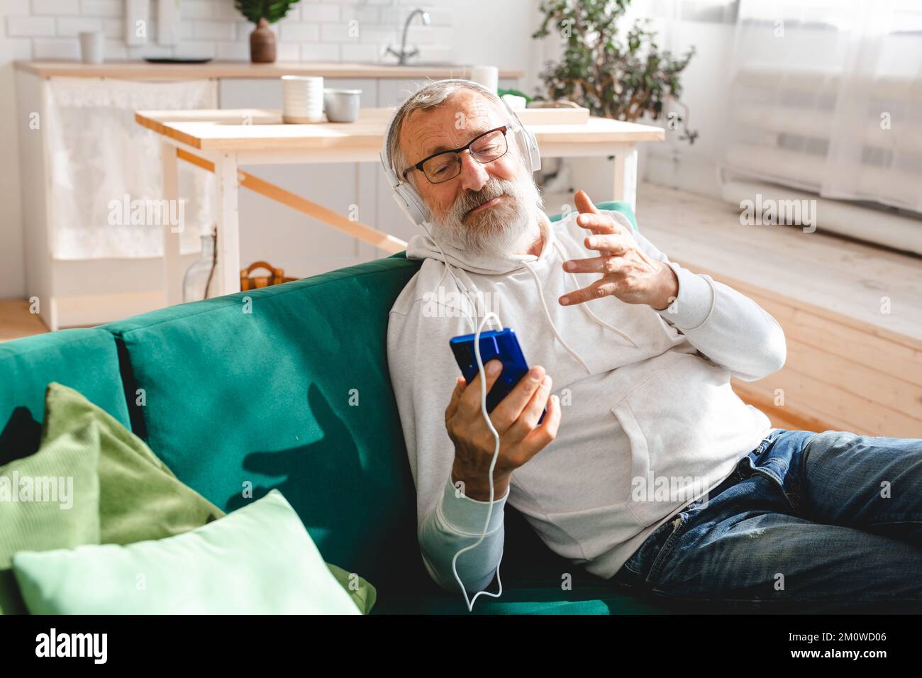 Elderly man making video call on smartphone in room waving to screen ...