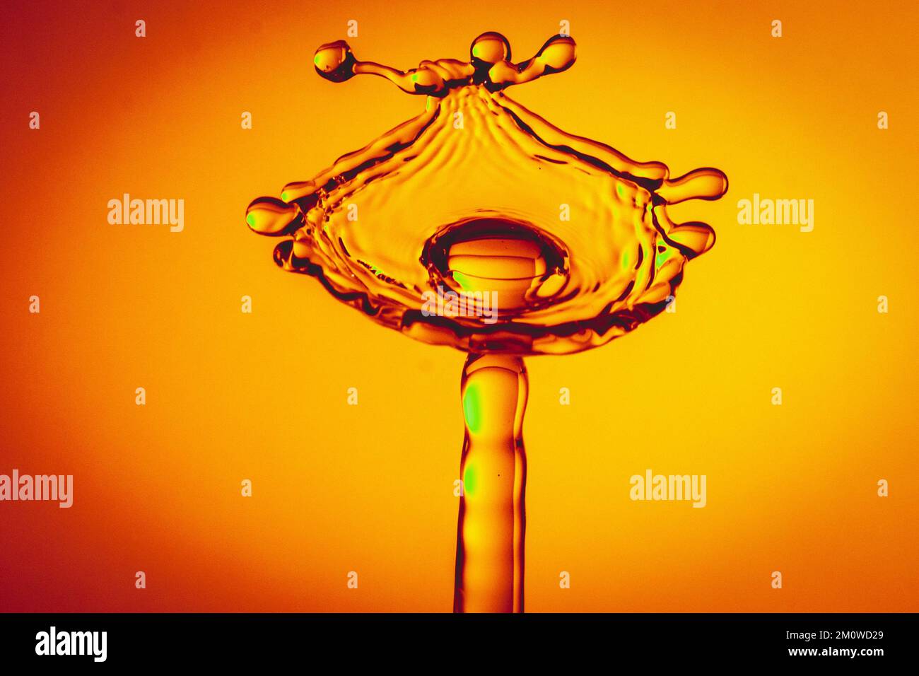 An amazing shot of a water drop splash forming a shape on an orange ...