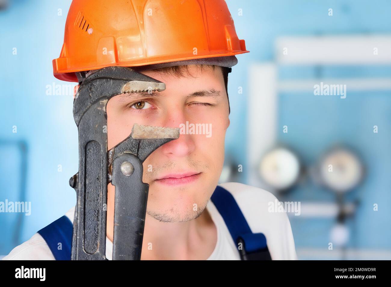 Professional plumber in helmet looks directly into camera through large ...