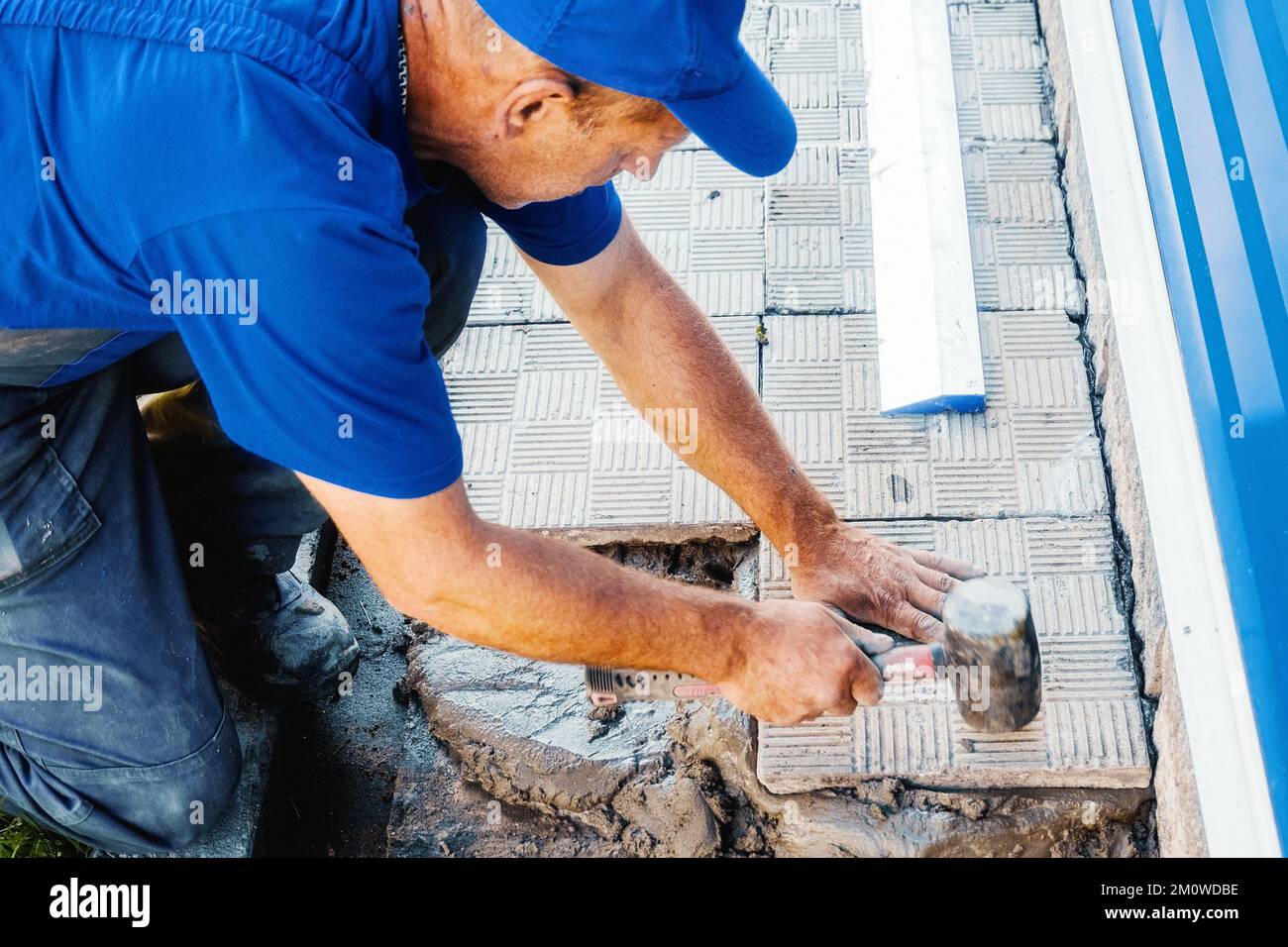 Bricklayer lays tiles. Professional builder in overalls and baseball ...