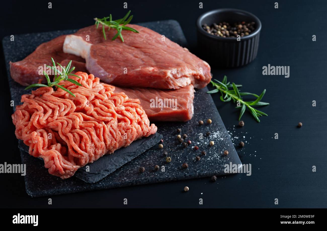 Fresh raw minced meat and cuts of beef, minced meat with herbs and ...