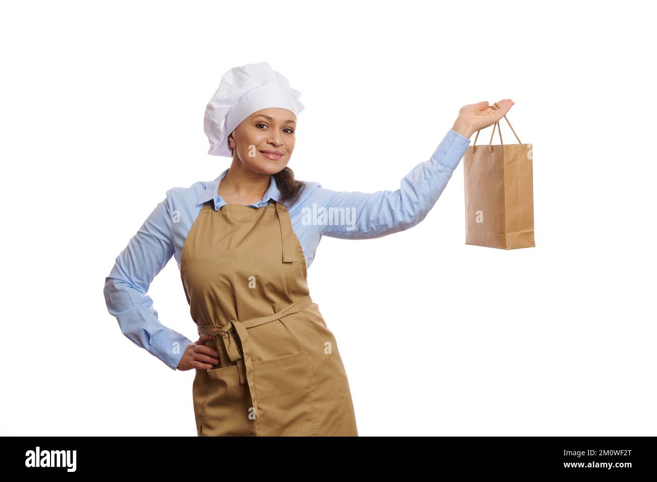 Charming woman waitress in chef's hat, blue shirt and beige apron ...