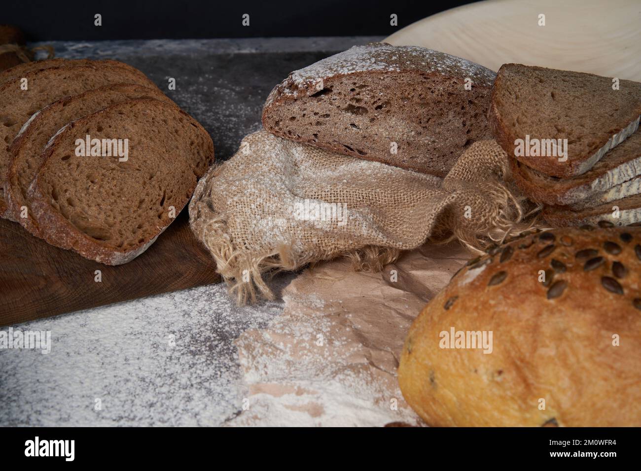 Different types of sliced bread and a loaf on a wooden background ...