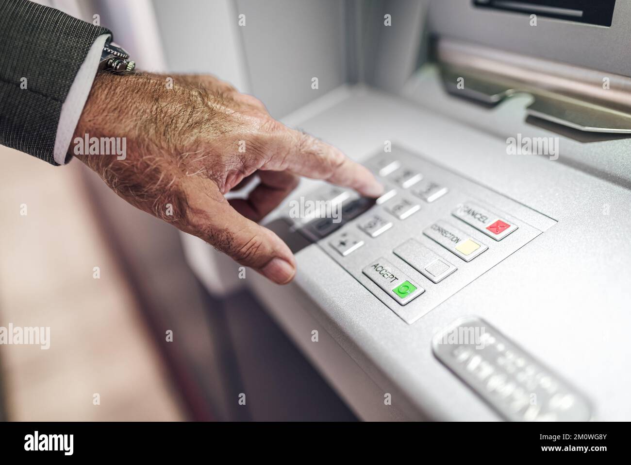 Close-up of senior male professional entering PIN in ATM machine ...