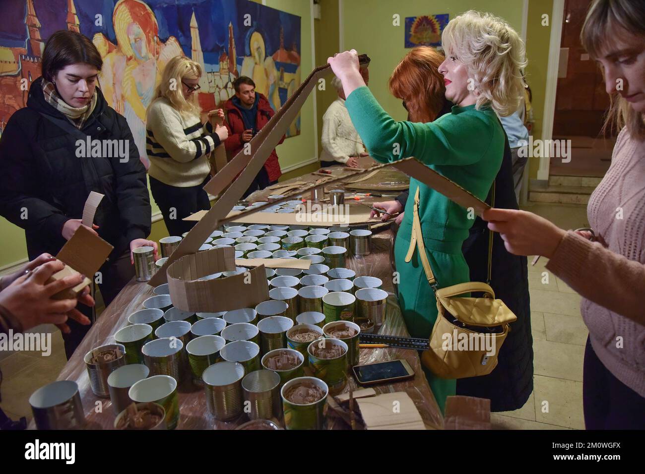 Volunteers cut cardboard and stuff it into prepared cans to make trench ...