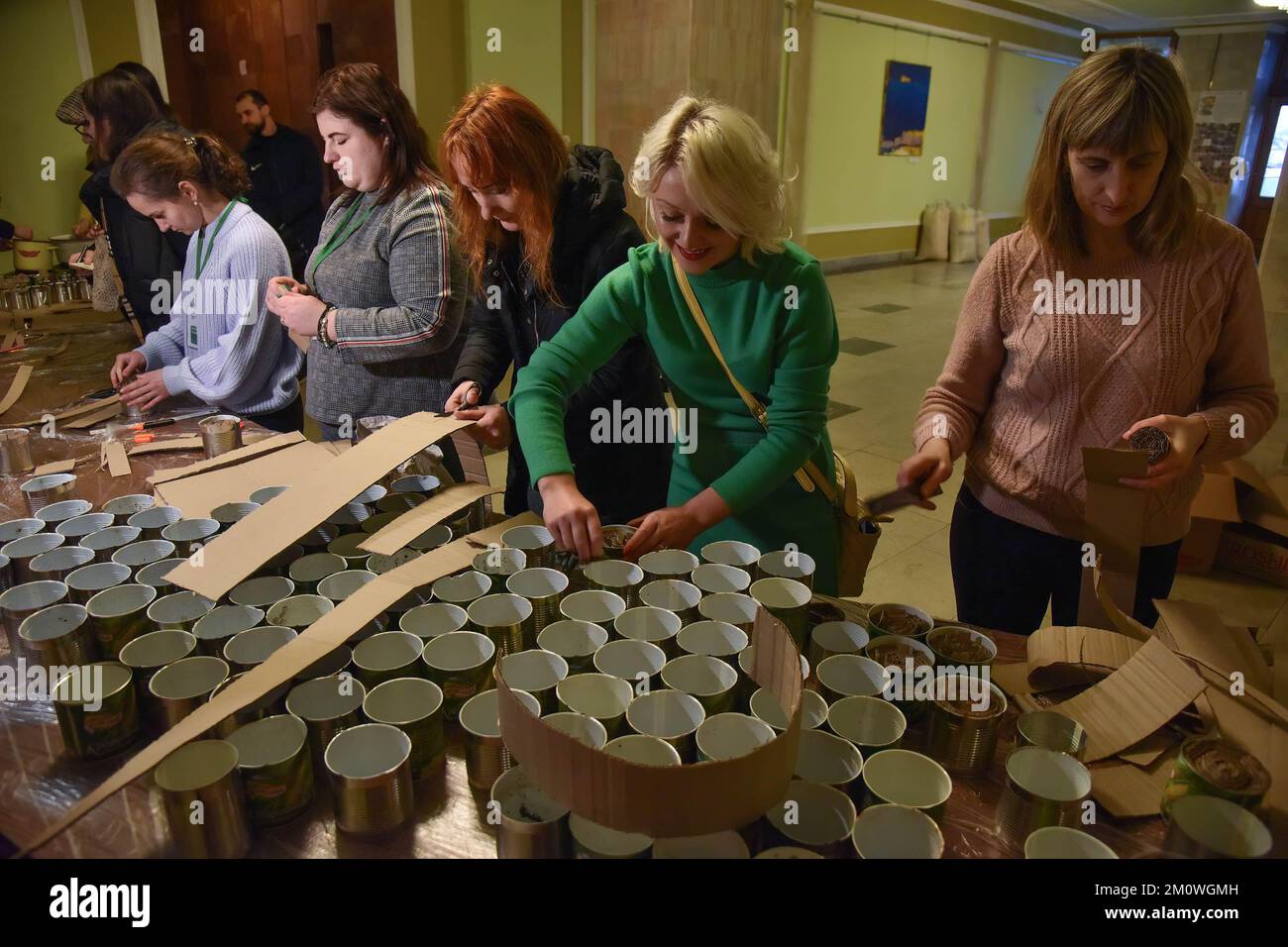 Volunteers cut cardboard and stuff it into prepared cans to make trench ...