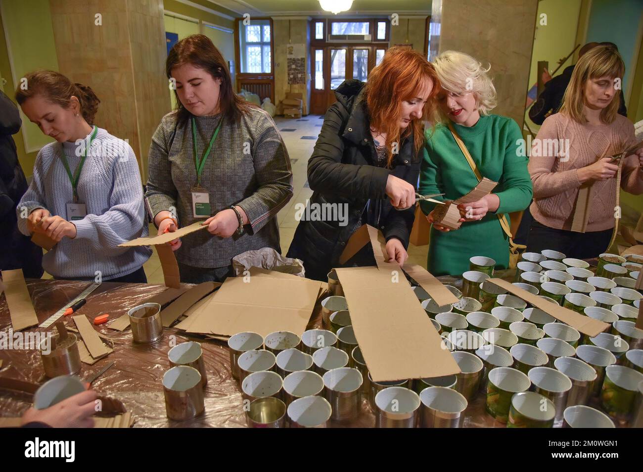 Volunteers cut cardboard and stuff it into prepared cans to make trench ...