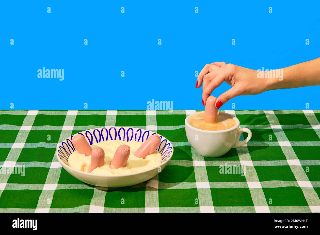 Plate with mashed potatoes and sausages on green tablecloth over blue ...