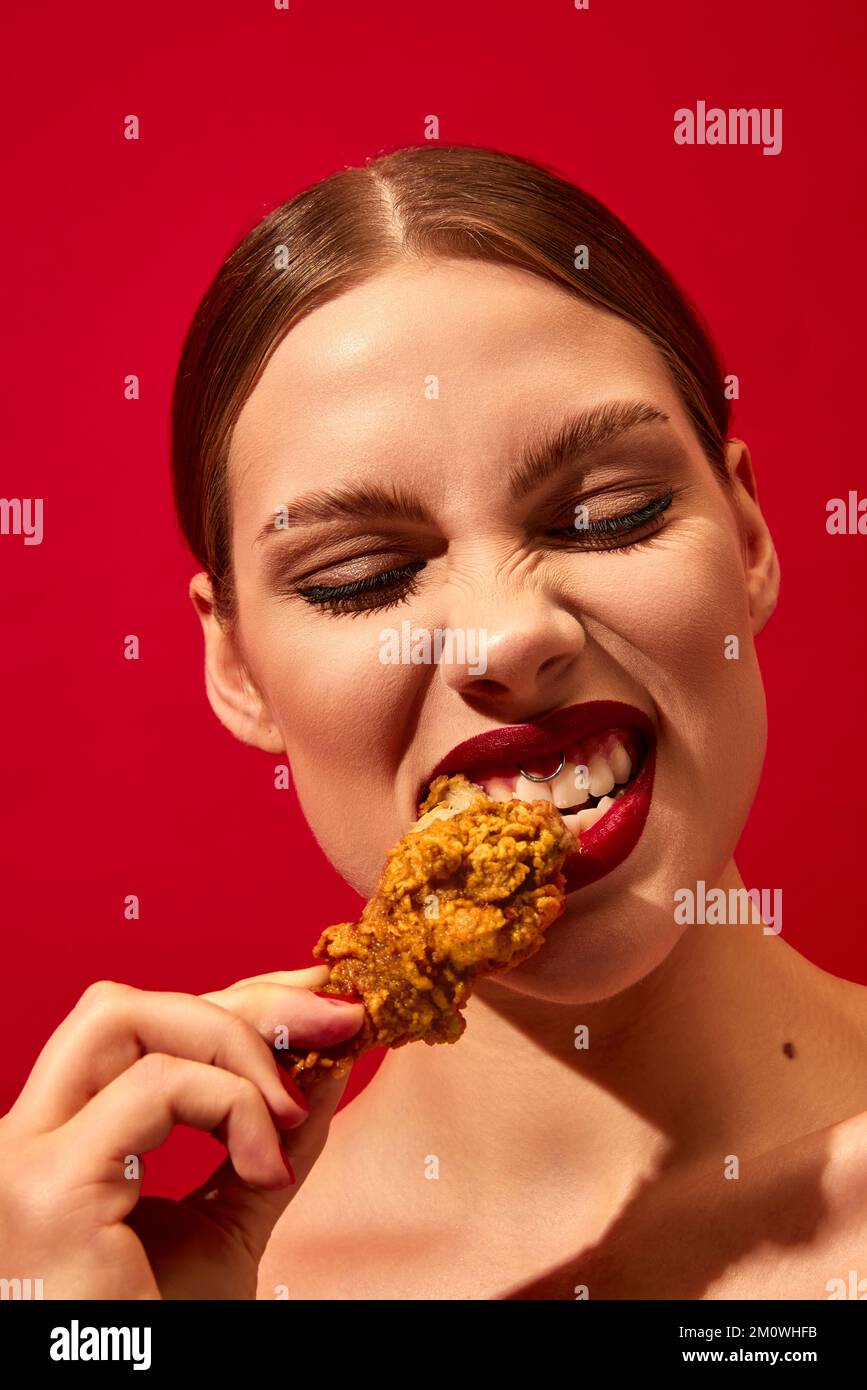 Young woman with red lipstick eating fried chicken, nuggets over vivid ...