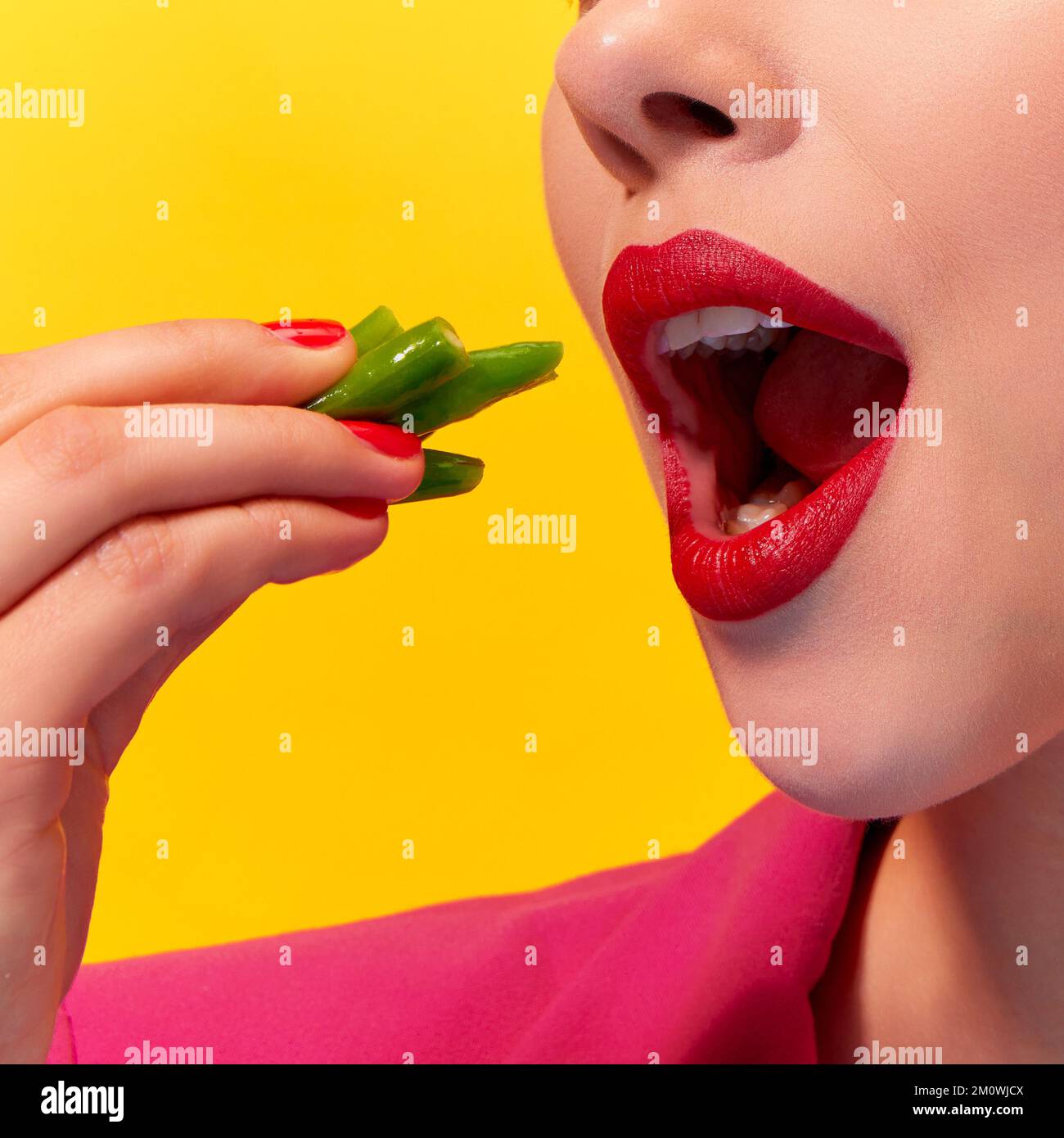 Cropped close up image of young woman, mouth with red lipstick eating ...