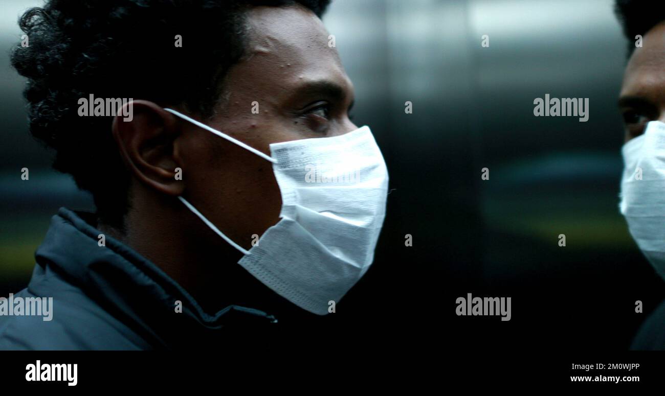 African american man putting on covid mask inside elevator, black ...