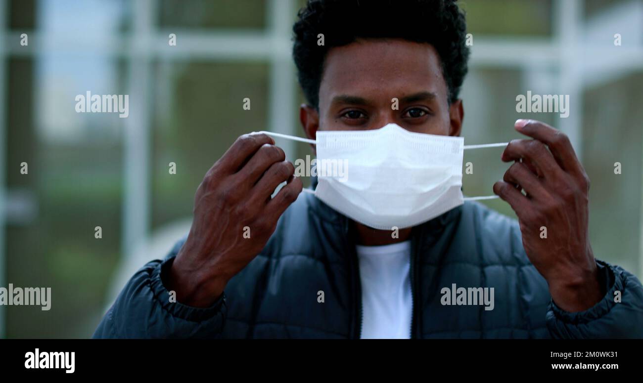 African man putting on covid mask walking forward to camera Stock Photo ...