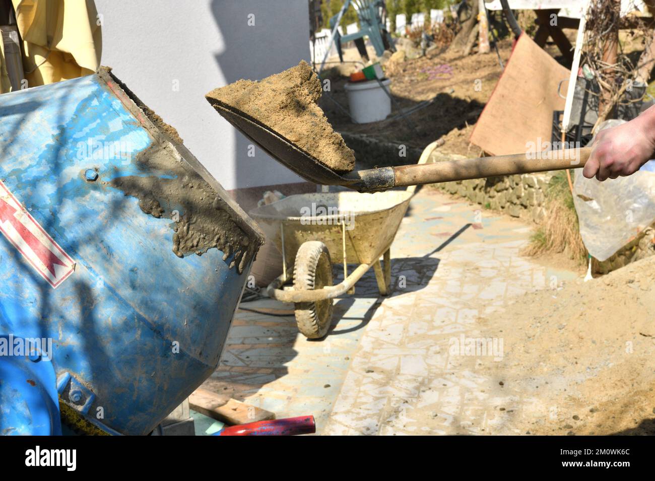 The mason loads the sand manually with a shovel into the concrete ...