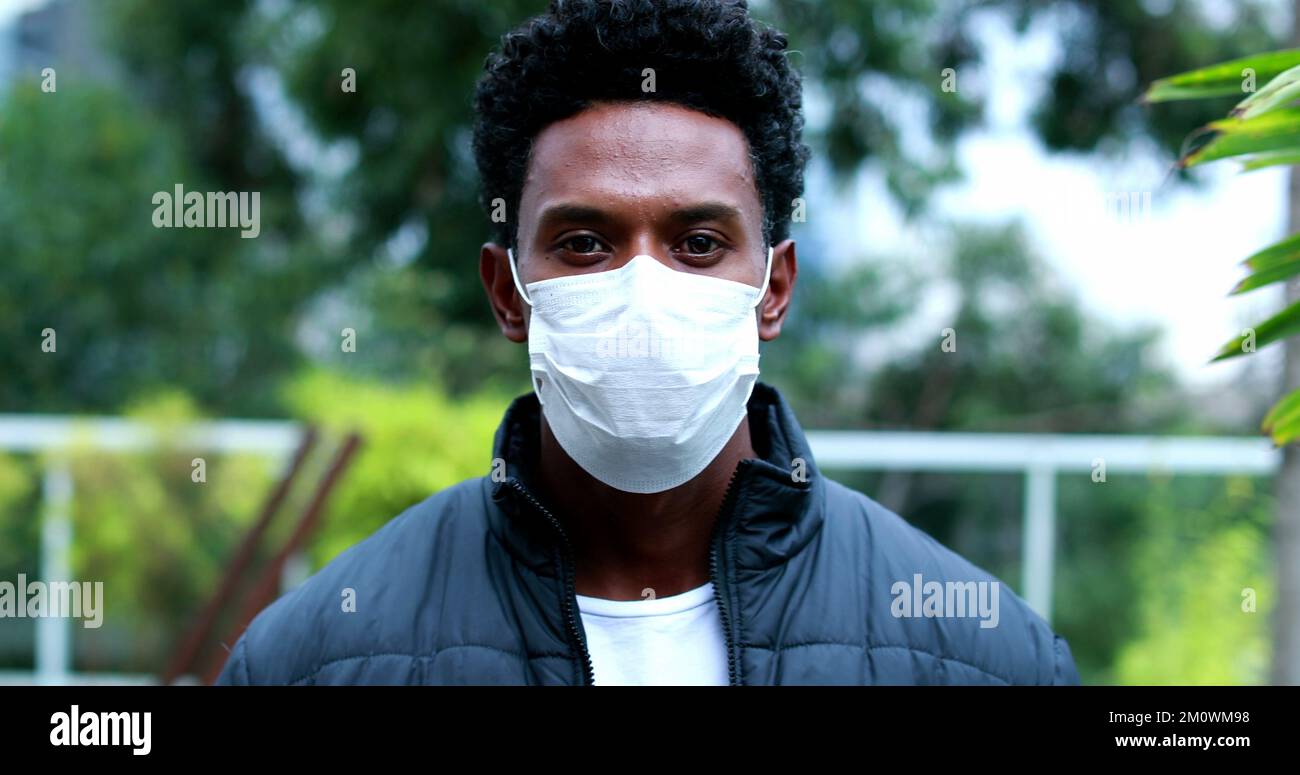 Portrait of black african man walking towards camera wearing covid mask ...