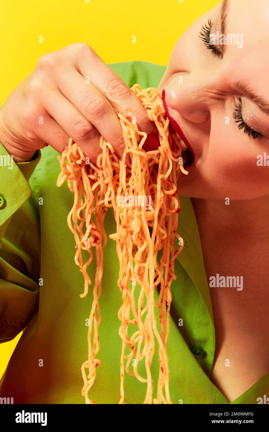 Close-up image of emotional young girl eating spaghetti, noodles with ...