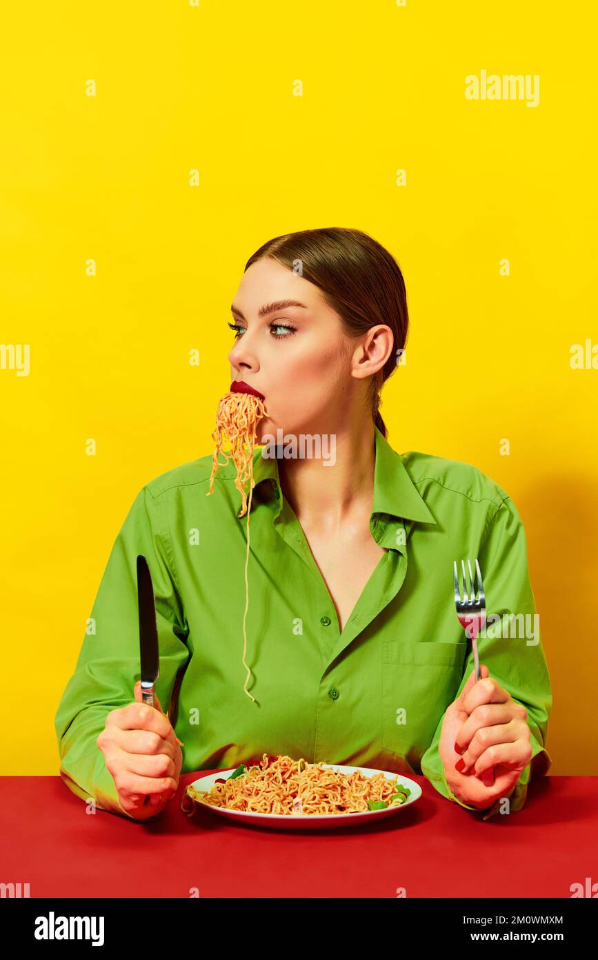Young girl eating spaghetti, noodles sticking out of the mouth over ...
