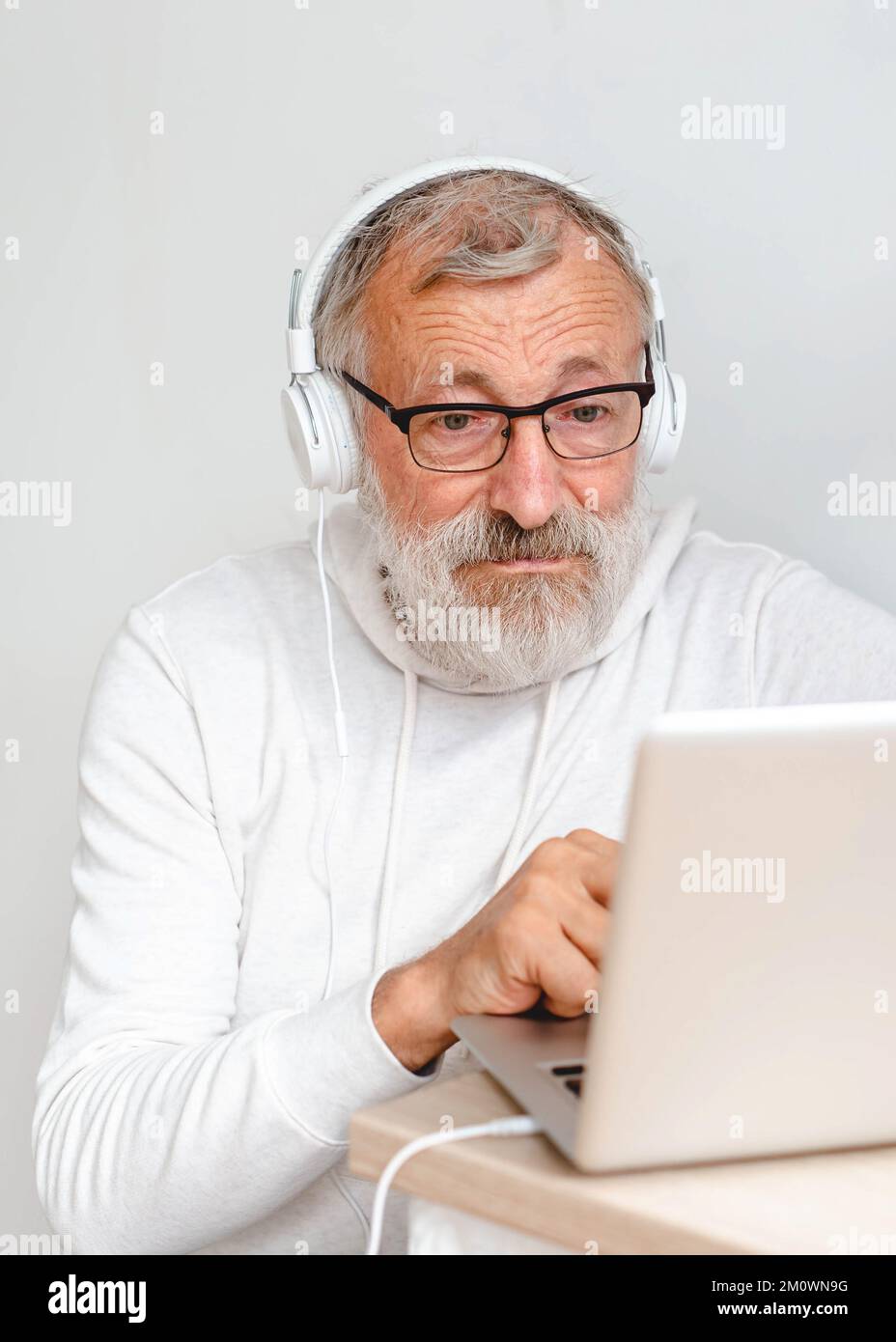 Portrait close-up handsome old man dressed in hoodie and eyeglasses is ...