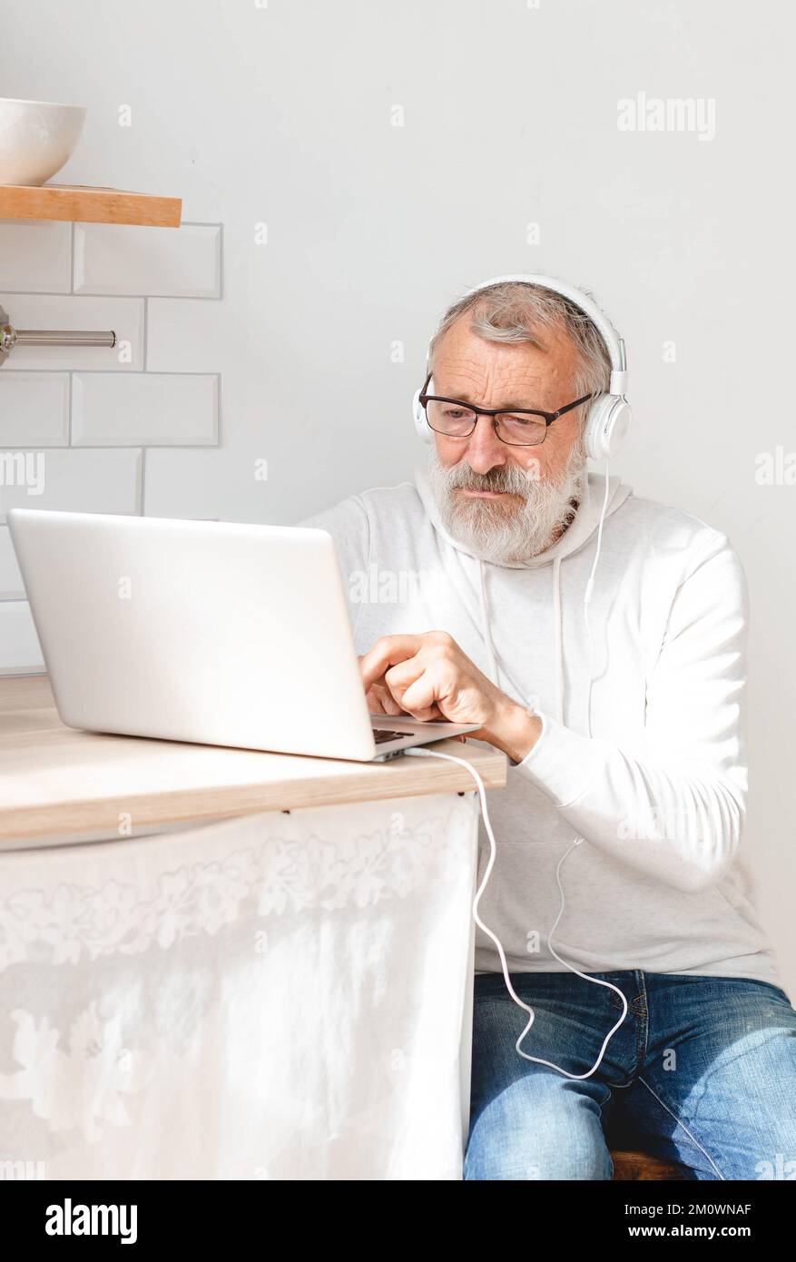 Portrait handsome old man dressed in hoodie and eyeglasses is using ...