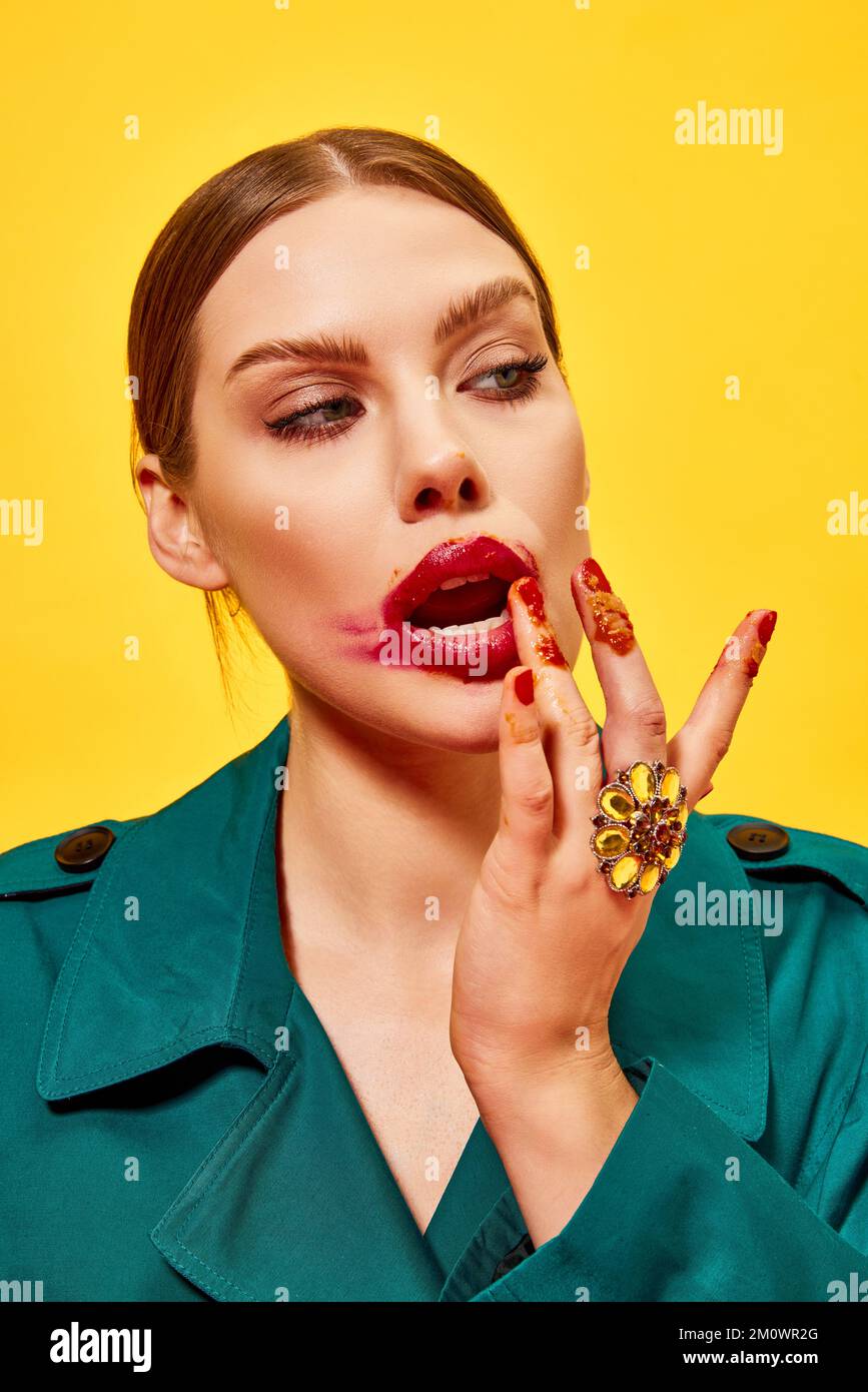 Young beautiful woman in green coat with smgged red lipstick licking ...