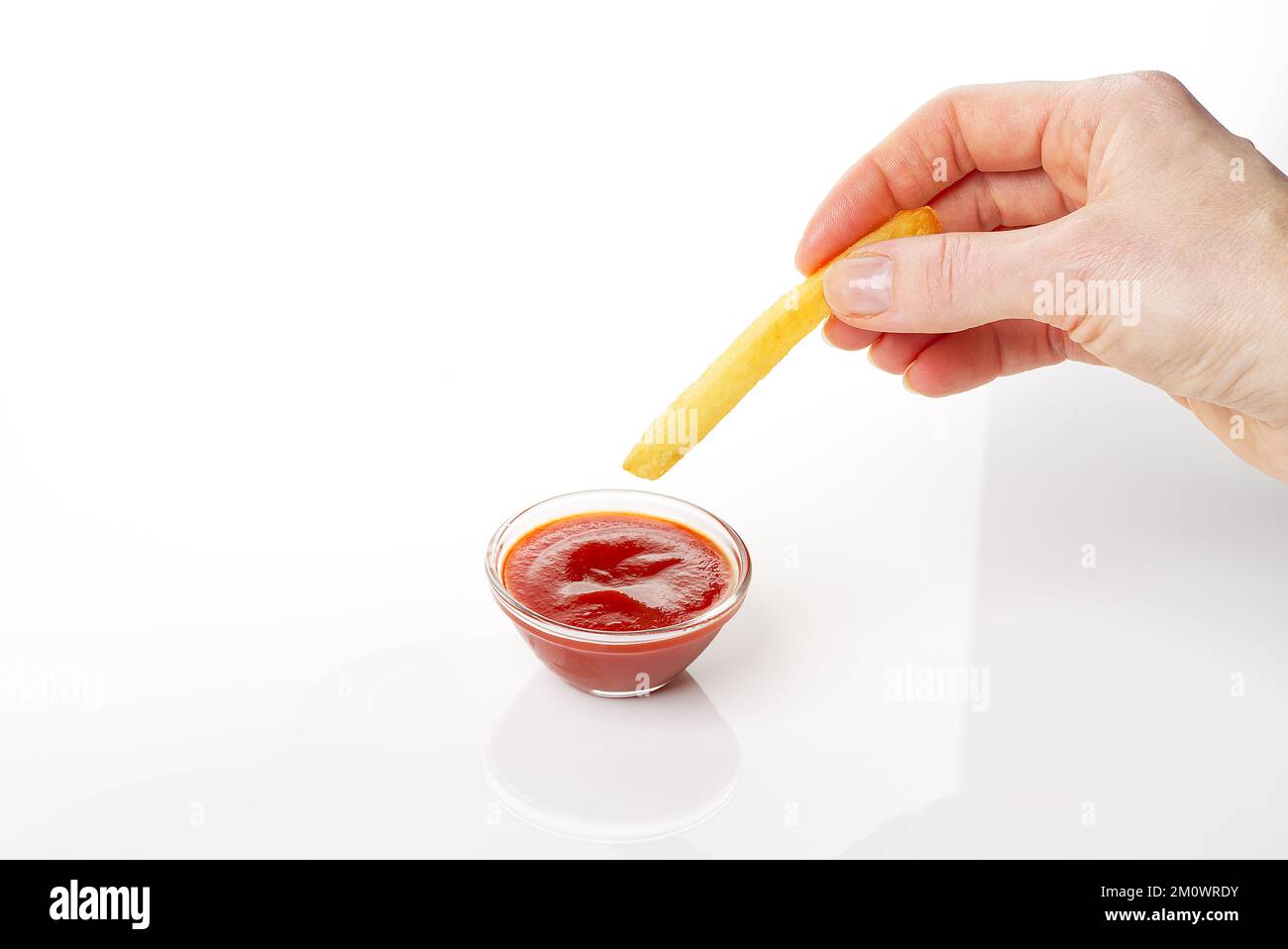 Hand dip french fries chips into ketchup isolated on white background ...
