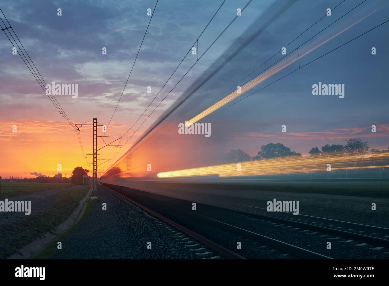 Modern railway at beautiful sunrise. Light trail of train on railroad ...