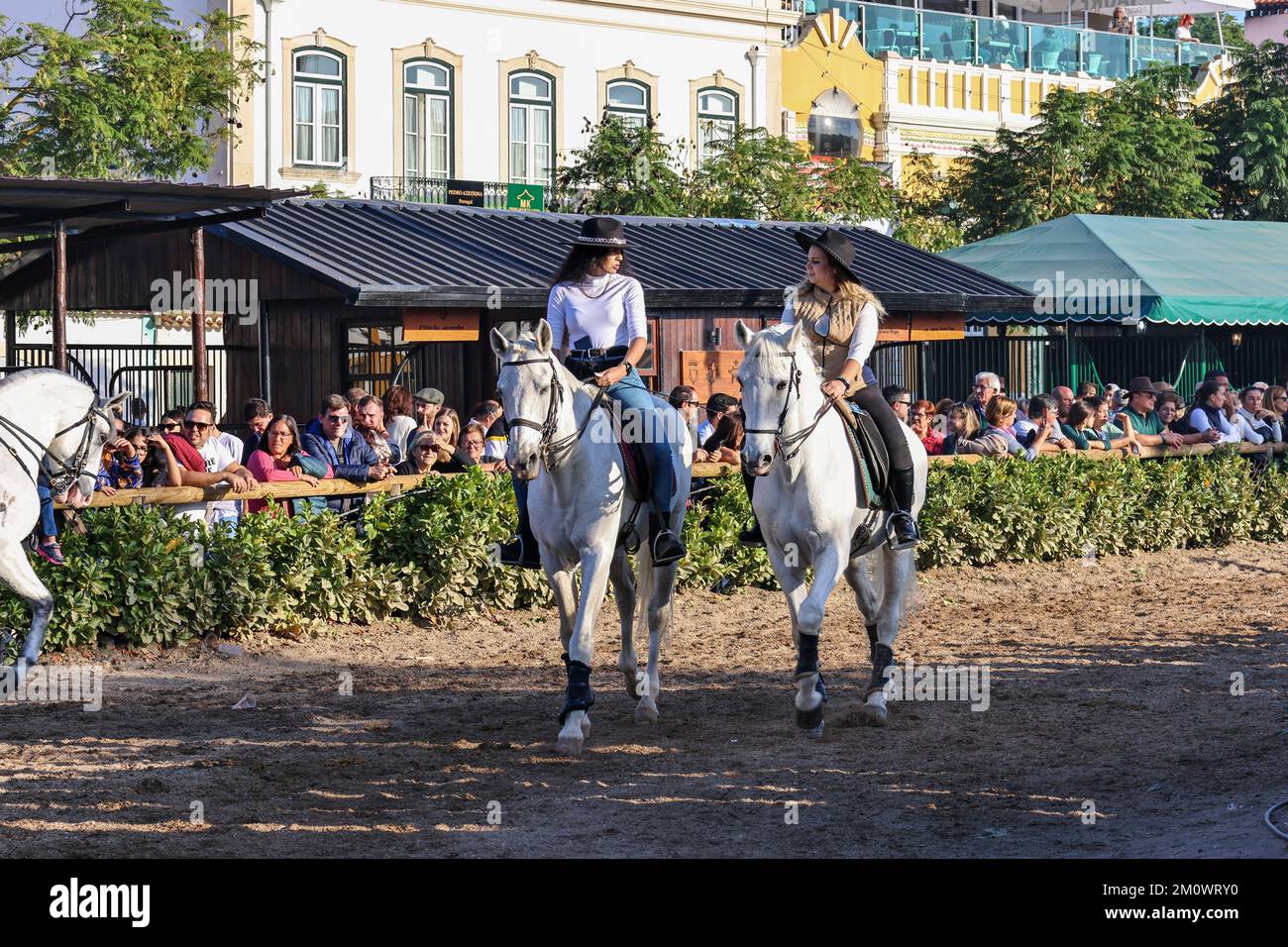 Two females riding white horses during the National horse fair, people ...