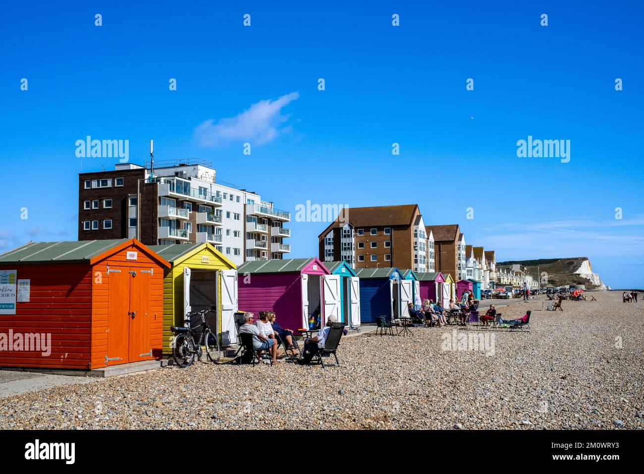 People Sitting Outside Colourful Beach Huts Seaford, East Sussex, UK ...