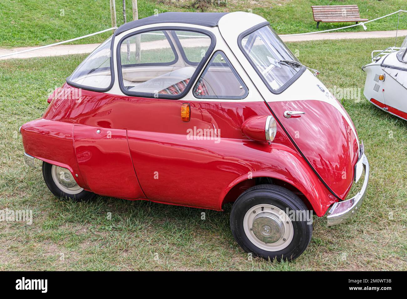A side view of a beautiful classic three-wheel red BMW Isetta 300 in a ...