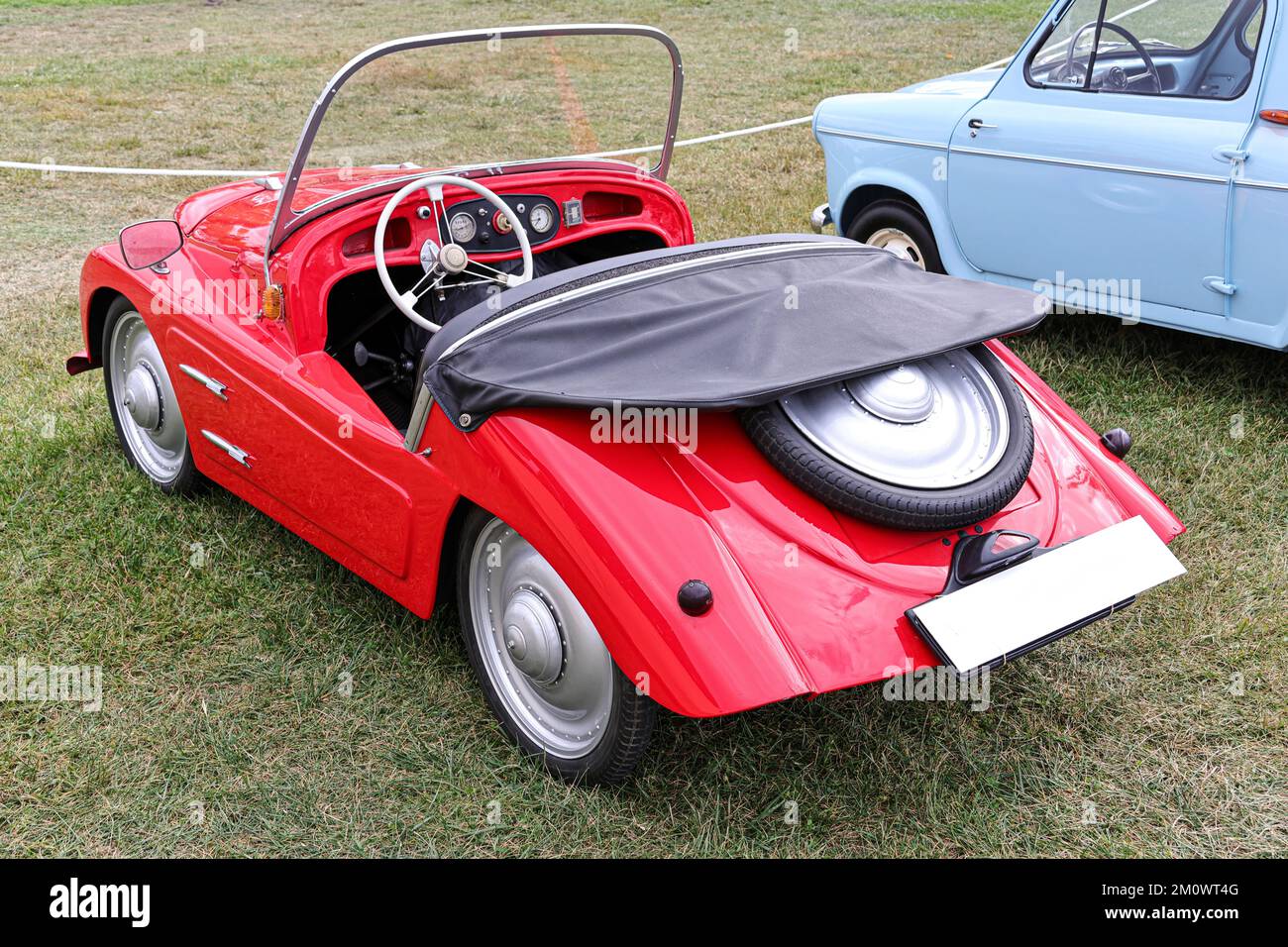 A rear view of a classic convertible red mini car with a folded roof in ...